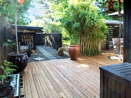 Um deck de madeira com vasos de plantas e uma cerca rústica.