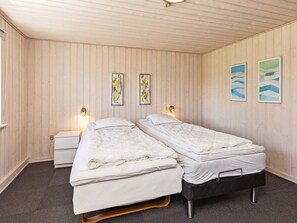 Quarto com duas camas, paredes de madeira e obras de arte.