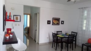 Uma área de refeições com uma mesa e cadeiras, uma cadeira branca, um balde vermelho e uma rosa vermelha sobre a mesa.