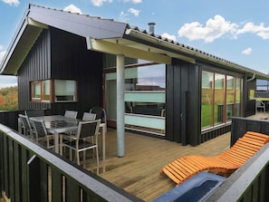 Um terraço moderno ao ar livre com área de jantar e cadeiras de descanso.