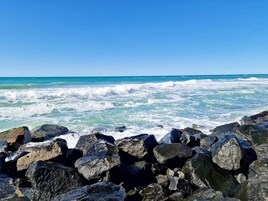 Uma costa rochosa com ondas quebrando nas pedras.