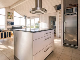 Cozinha moderna com ilha central, eletrodomésticos de aço inoxidável e vista para o exterior.
