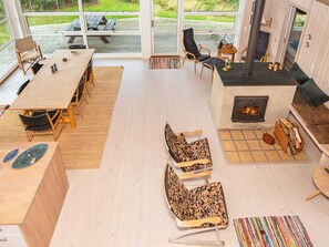 Uma sala de estar espaçosa com lareira, mobiliário de madeira e grandes janelas com vista para um jardim.