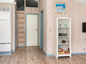 Quarto com guarda-roupa branco, escada, porta e estante branca com diversos objetos.
