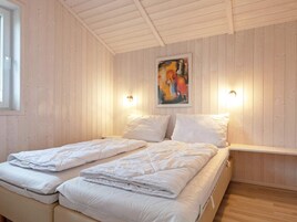 Quarto com duas camas, paredes de madeira, um quadro e duas luzes na parede.