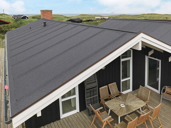 Um terraço com mesa e cadeiras, um espaço de varanda coberto e vista para a paisagem ao redor.