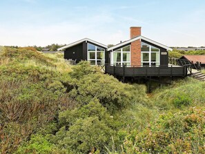 Edifício moderno com terraço, cercado por vegetação densa.
