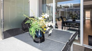 Uma varanda com mesa, cadeiras e um vaso de planta.