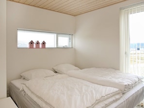 Quarto com duas camas, uma janela com persianas e vista para o exterior.