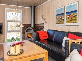 Uma sala de estar aconchegante com lareira, um sofá de couro e uma mesa de madeira com velas.