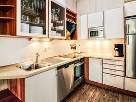 Cozinha compacta com lava-louças, forno, micro-ondas e cafeteira.