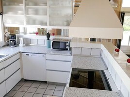 Cozinha compacta com armários brancos, lava-louças, micro-ondas e pia.