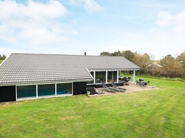 Uma casa com varanda coberta, piscina e quintal gramado.