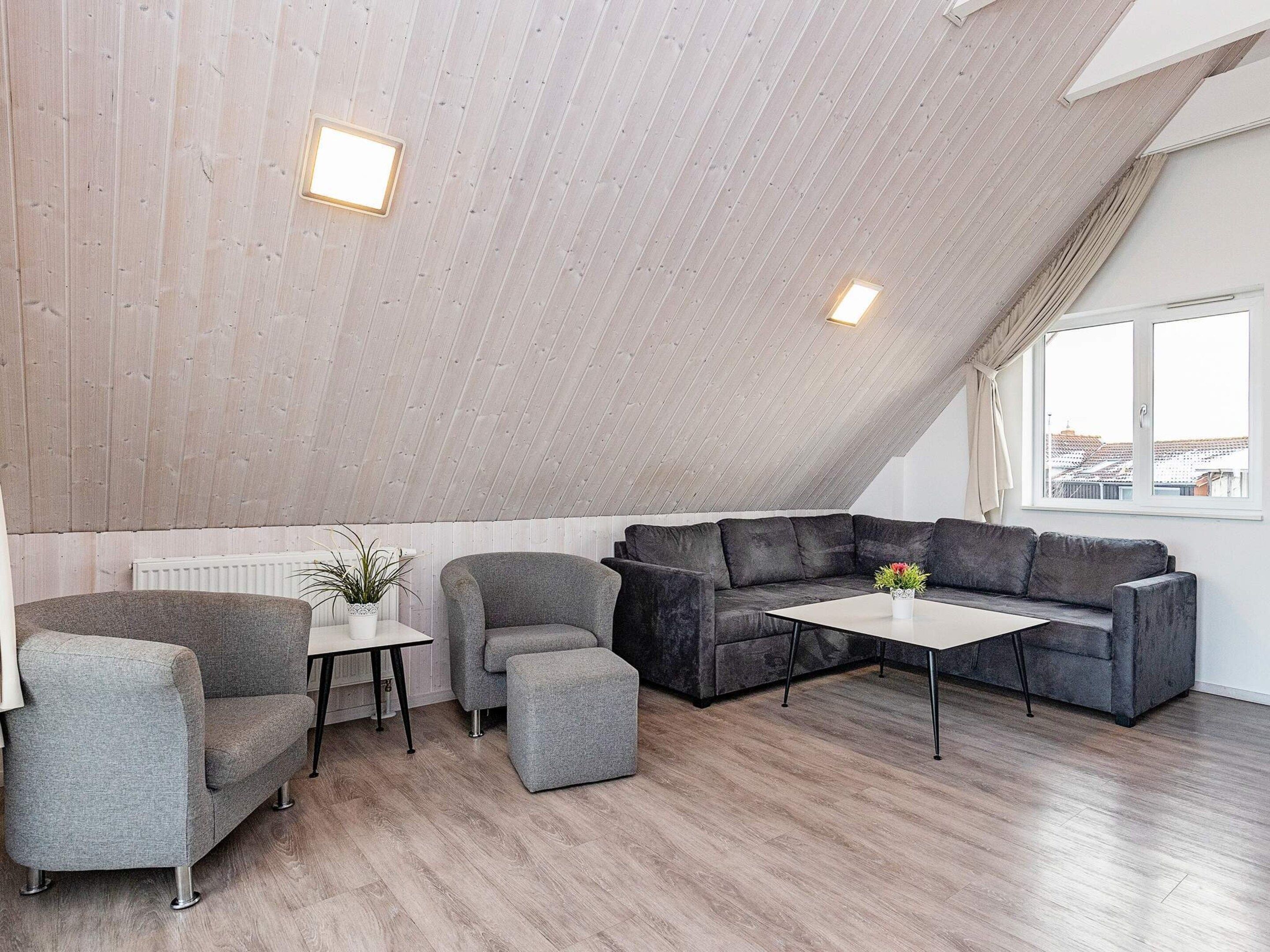 Um espaço de estar moderno estilo loft, com teto inclinado, sofá modular, mesinha e planta em vaso.