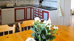Uma cozinha com armários brancos, uma mesa de madeira e uma planta em vaso.