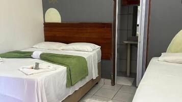 Quarto de hotel com duas camas, uma cabeceira de madeira, um tapete branco e uma parede com um mural floral.