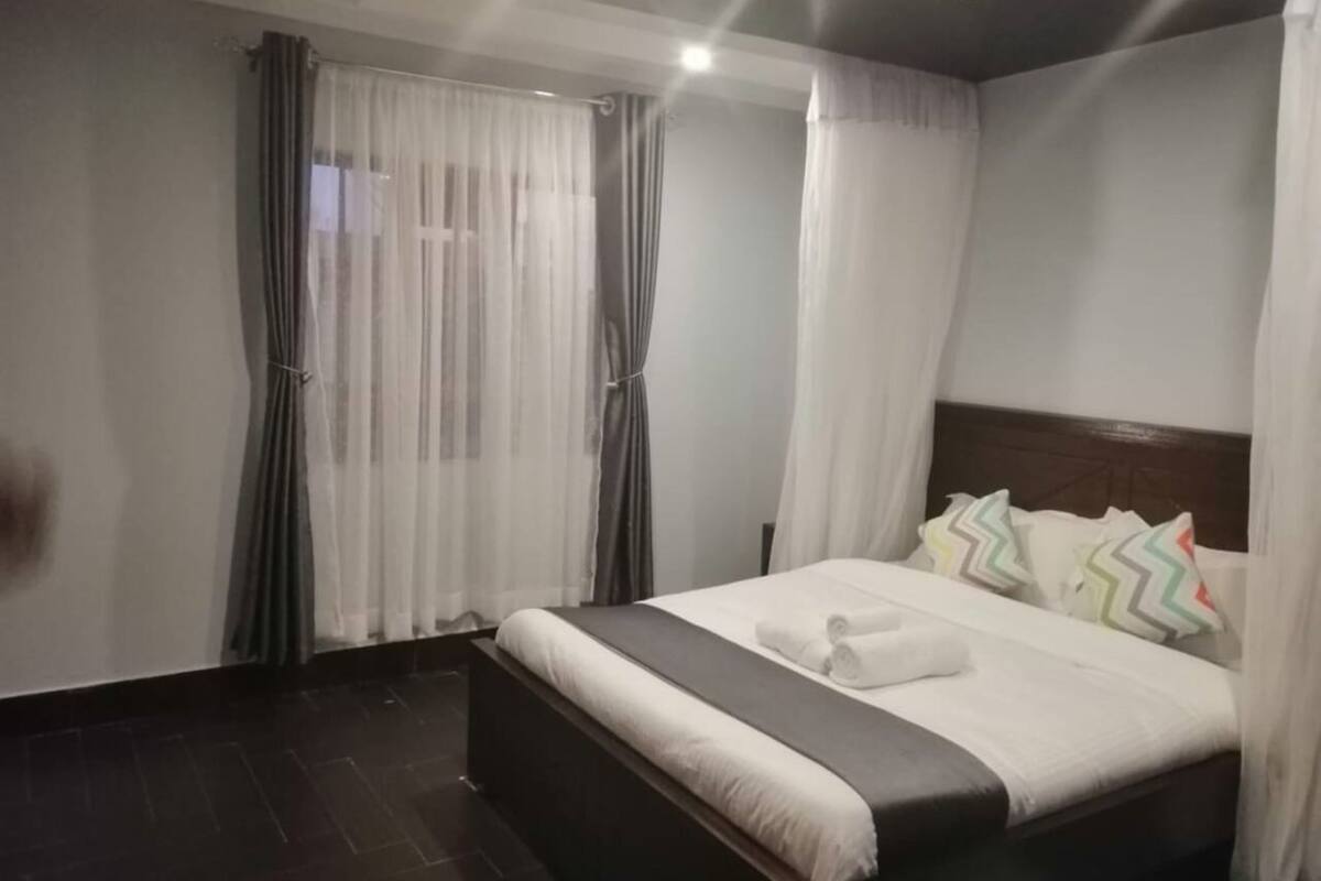 Quarto de hotel com cama, cortinas e cabeceira.