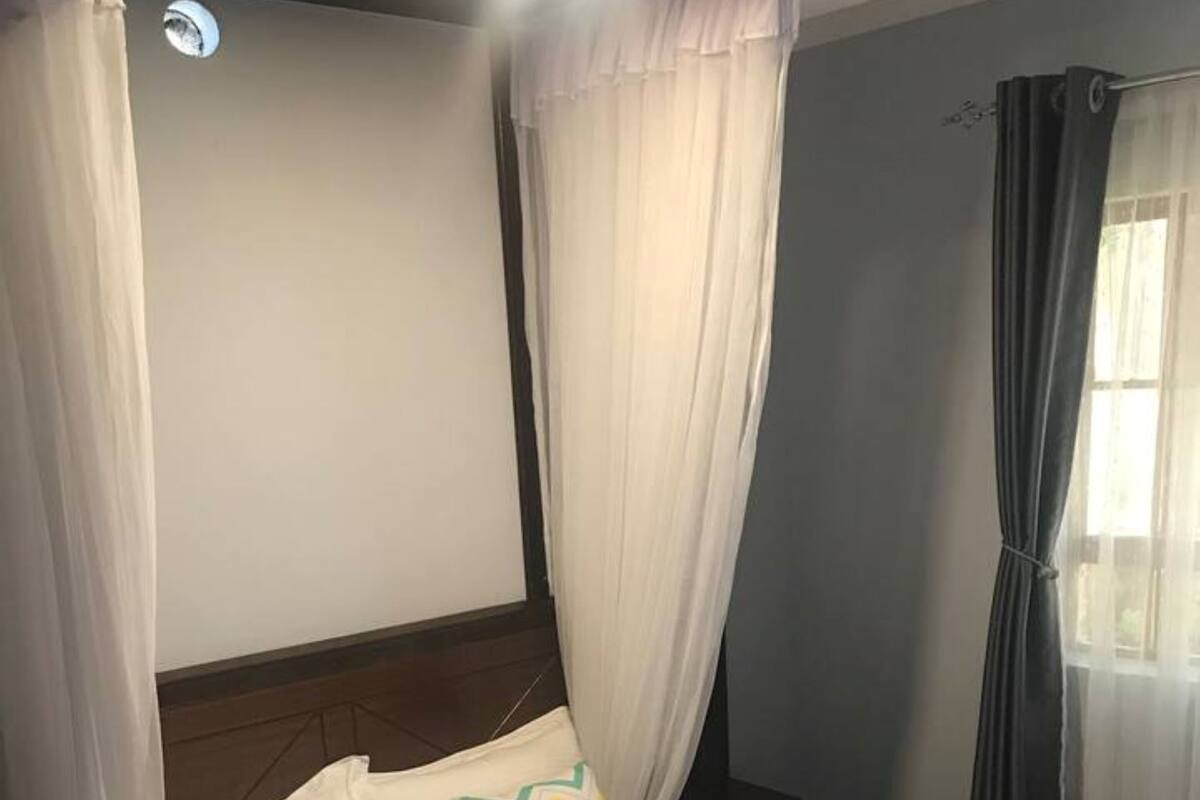 Cama bem arrumada com um edredom branco, duas almofadas e uma toalha dobrada.