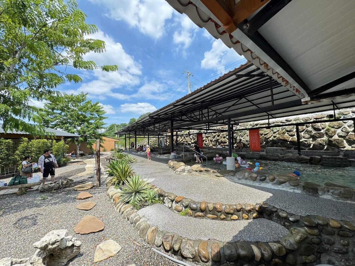 Uma área externa coberta com muro de pedra, um caminho e uma pequena piscina.