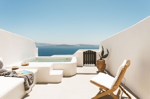 Terraço iluminado pelo sol com hidromassagem, área de estar e vista para o mar.