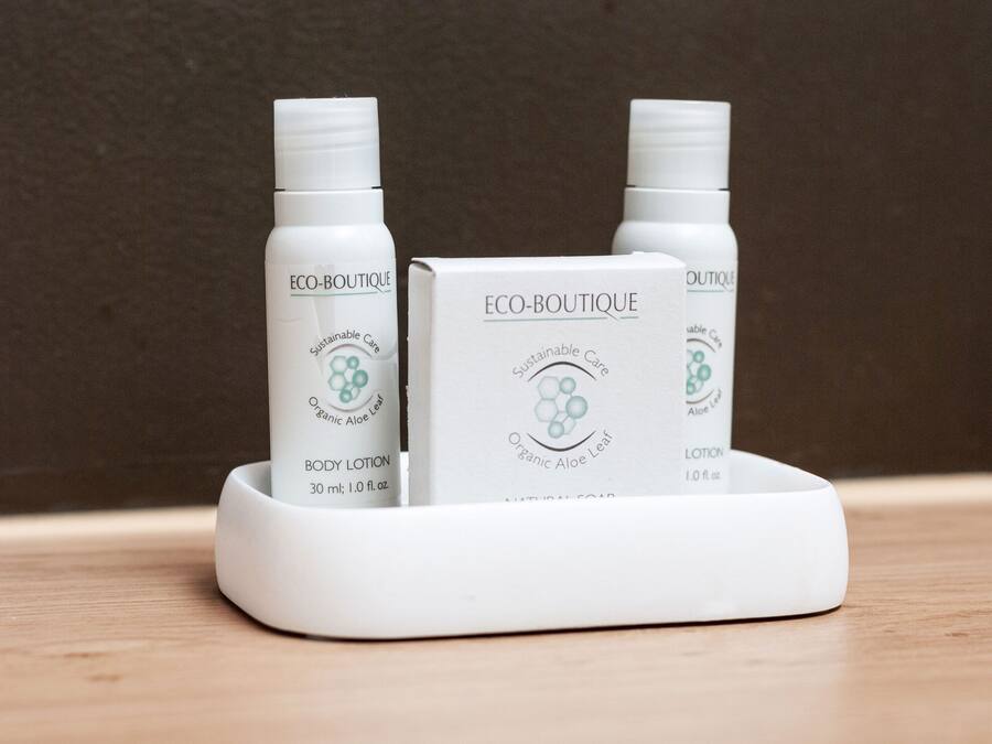 Uma bandeja branca com dois frascos de loção corporal ECO-BOUTIQUE e uma caixa, tudo com um logotipo verde.