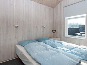 Quarto com cama, mesa de cabeceira, decoração em formato de coração e janela.