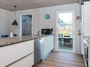 Cozinha moderna com bancada de granito, eletrodomésticos de aço inoxidável e vista para o exterior.