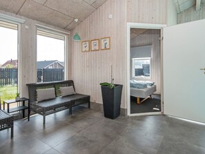 Quarto com sofá, cama, planta em vaso e janela.