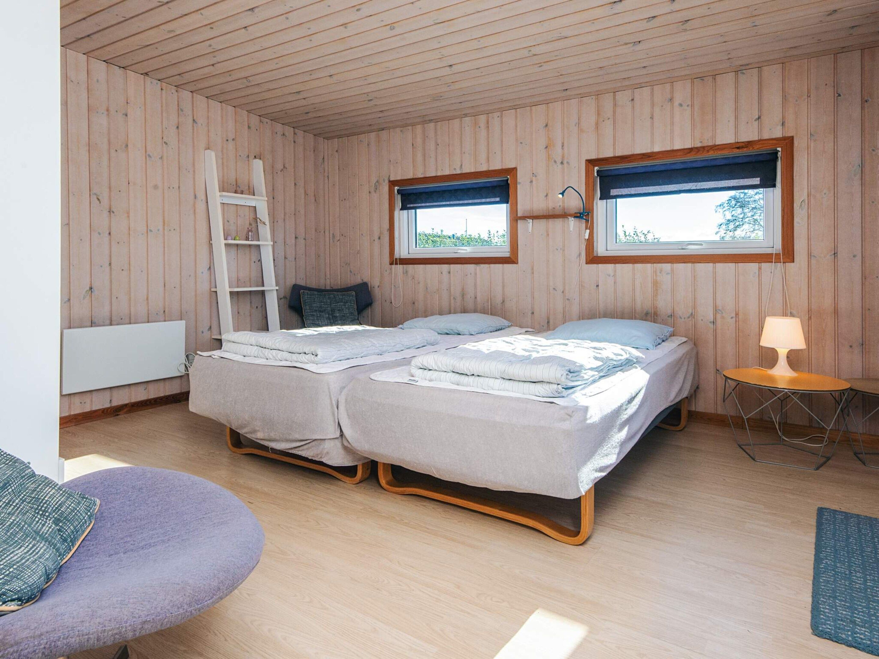Quarto com duas camas, uma cadeira, uma mesa e uma janela.
