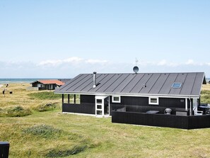 Um edifício moderno preto com telhado plano, antena parabólica e uma janela pequena.