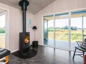 Interior moderno com lareira a lenha, uma grande porta de correr de vidro e vista para o exterior.