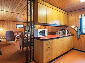 Cozinha compacta com armários de madeira, micro-ondas e cafeteira.