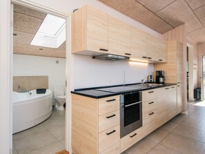 Cozinha moderna com armários de madeira, bancada preta e forno embutido.