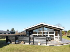Uma casa moderna com um deck espaçoso, um alpendre coberto e uma garagem.