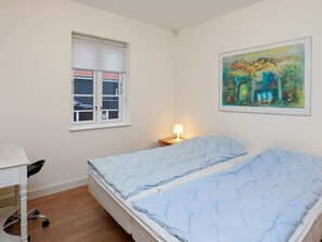 Quarto com cama, escrivaninha, janela e um quadro.