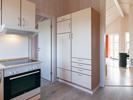 Cozinha moderna com armários brancos, forno Siemens e teto de madeira.