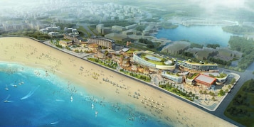 Resort costeiro com praia, edifícios modernos e um rio.