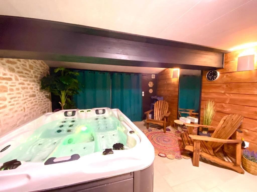 Uma banheira de hidromassagem em um quarto com paredes de madeira, uma parede de destaque em pedra e teto com vigas aparentes.