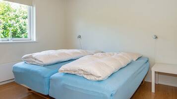 Quarto com uma cama, uma janela e uma parede branca.