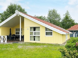Edifício amarelo com telhado vermelho, área de estar coberta ao ar livre e placa com o número 44.