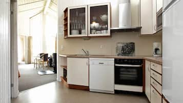 Cozinha compacta com máquina de lavar louça, forno e cafeteira.