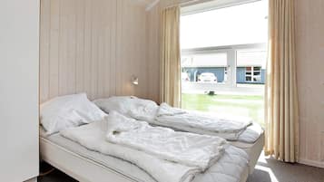 Quarto com duas camas, janela com cortinas e vista para um edifício.