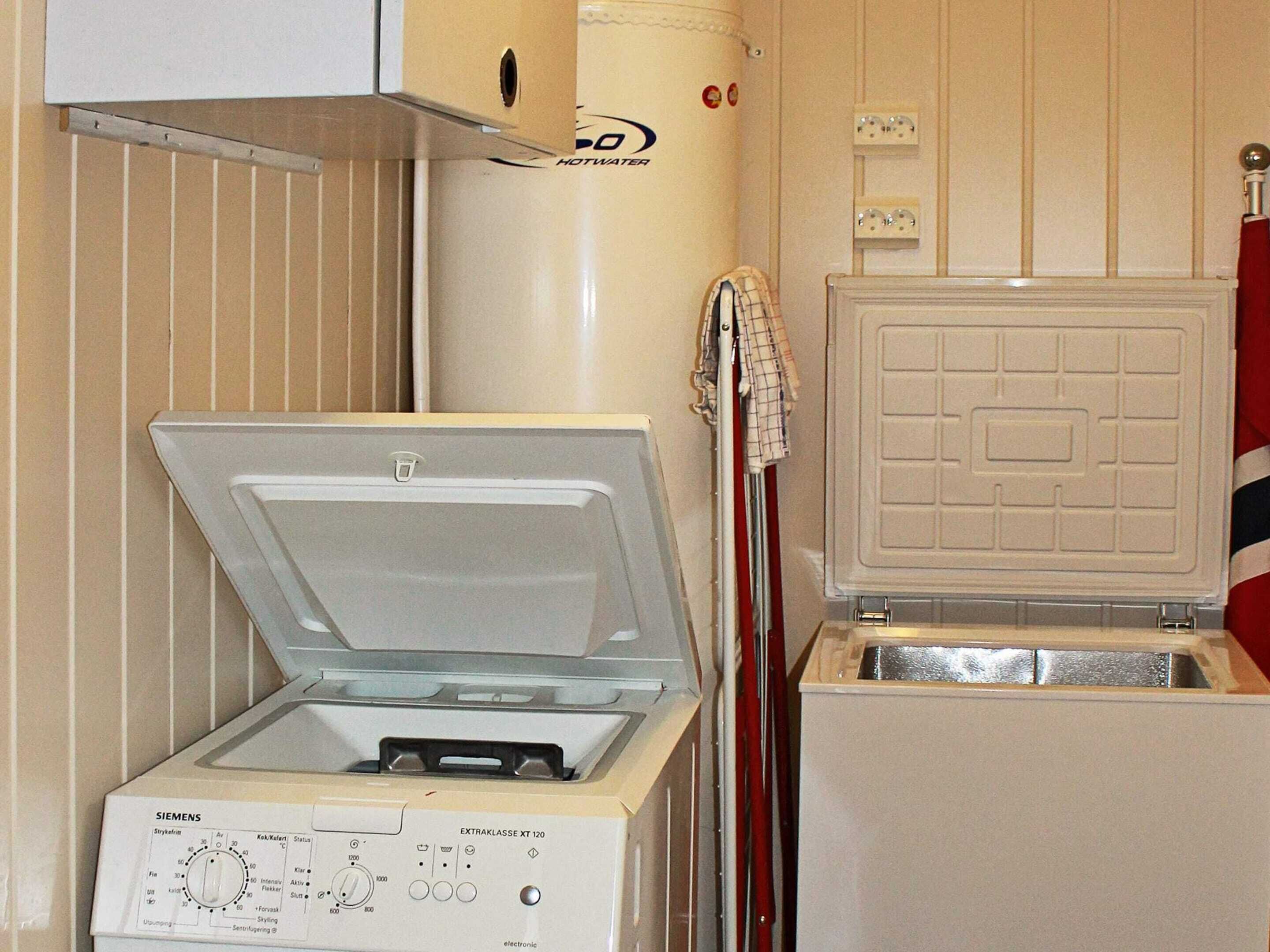 Uma lavanderia compacta com máquina de lavar Siemens, aquecedor de água e pia embutida.