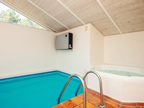 Uma piscina com deck ladrilhado e uma banheira de hidromassagem.