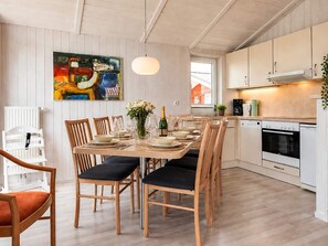 Uma cozinha moderna com armários de madeira, uma mesa de jantar posta para quatro pessoas e um grande quadro abstrato na parede.
