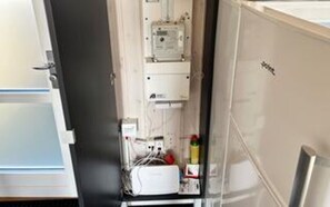 Quarto com cozinha compacta, incluindo micro-ondas, pequena geladeira e tomadas elétricas.