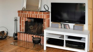 Sala de estar com lareira de tijolos, televisão de tela plana sobre um suporte e um módulo de entretenimento branco com prateleiras.