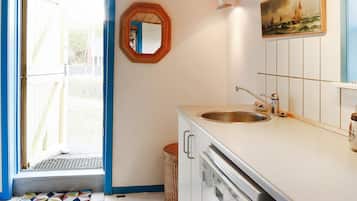 Cozinha compacta com pia, lava-louças e janela com vista para o exterior.