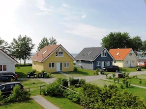 Um bairro residencial com casas, um acesso pavimentado e carros estacionados.