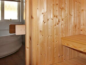 Uma sala de sauna de madeira com um banco de madeira e uma janela.